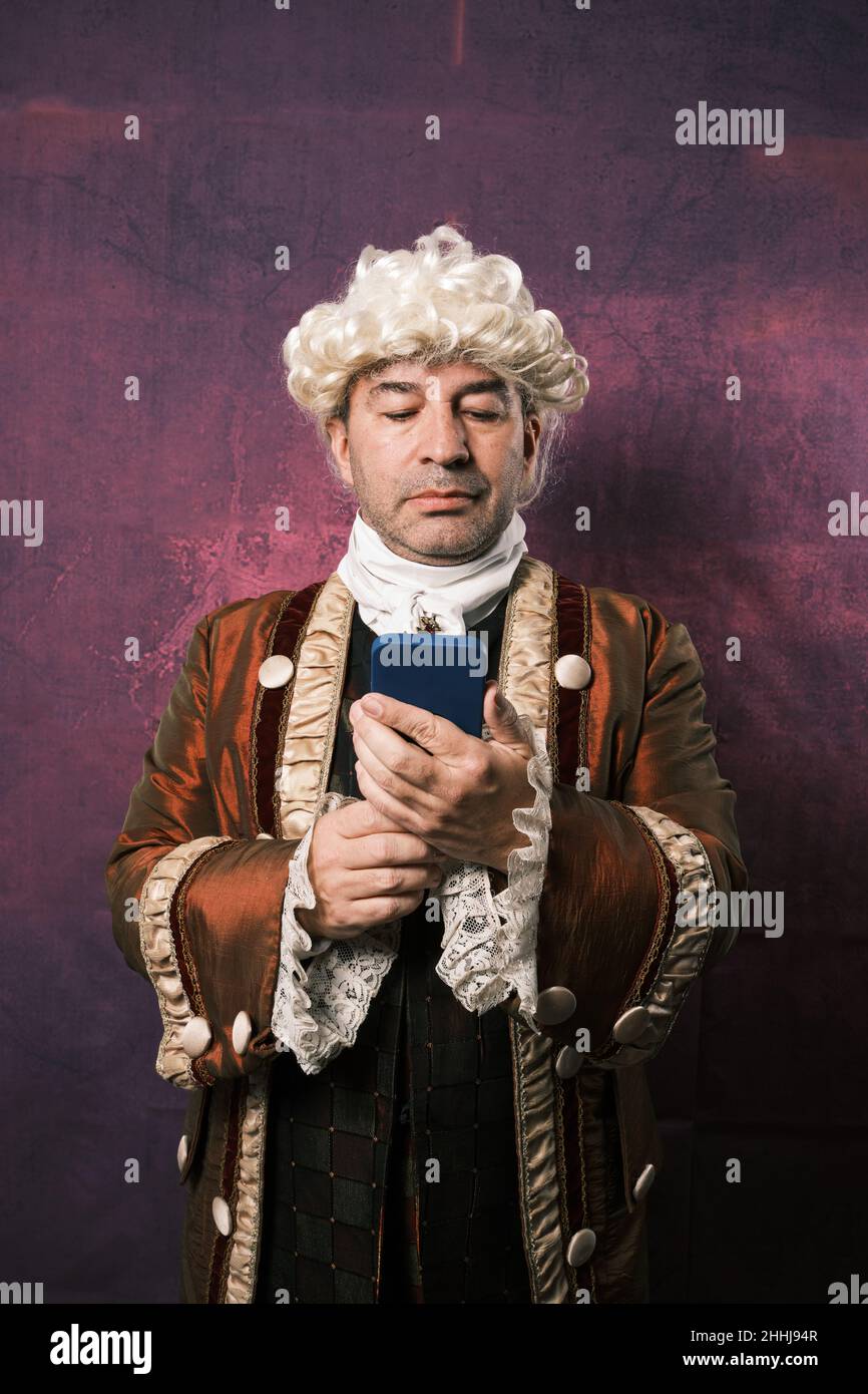 Man in classical renaissance clothes using a mobile phone while ...