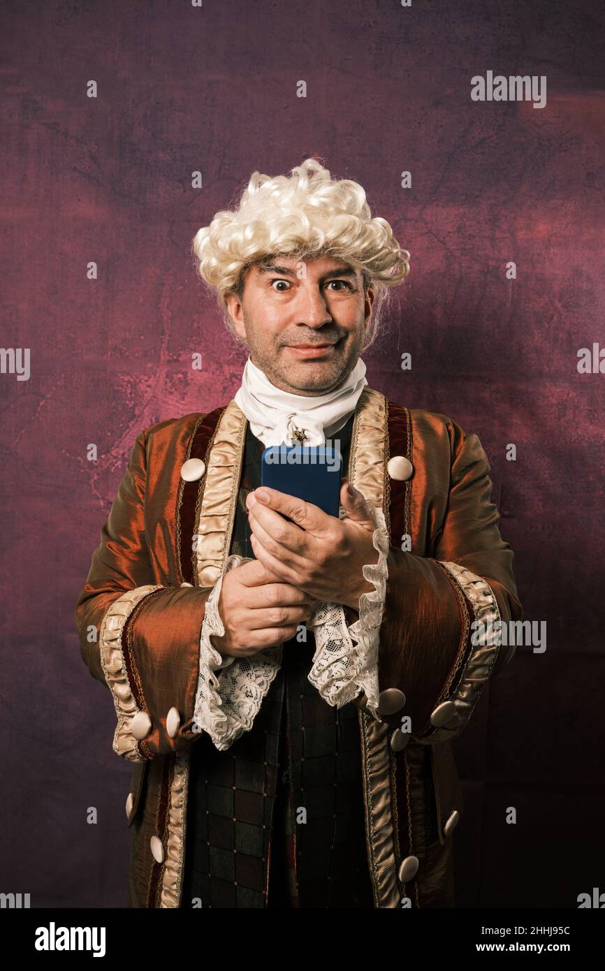 Man in classic medieval clothes looking at camera while using a mobile ...