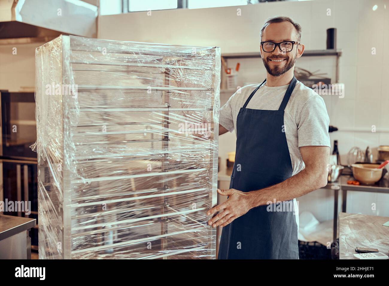 Cheerful male worker standing by showcase in cafe Stock Photo - Alamy
