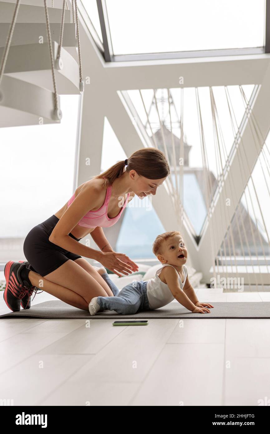 Happy child lying on a sports mat next to his mom Stock Photo - Alamy