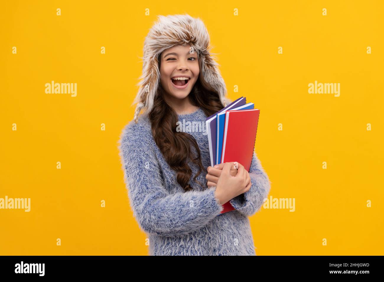 happy winking kid long hair in hat with copybook on yellow background ...