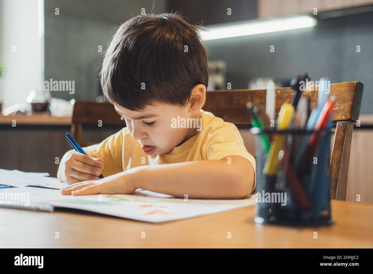 Caucasian little boy learning alphabet. Boy writing homework ...