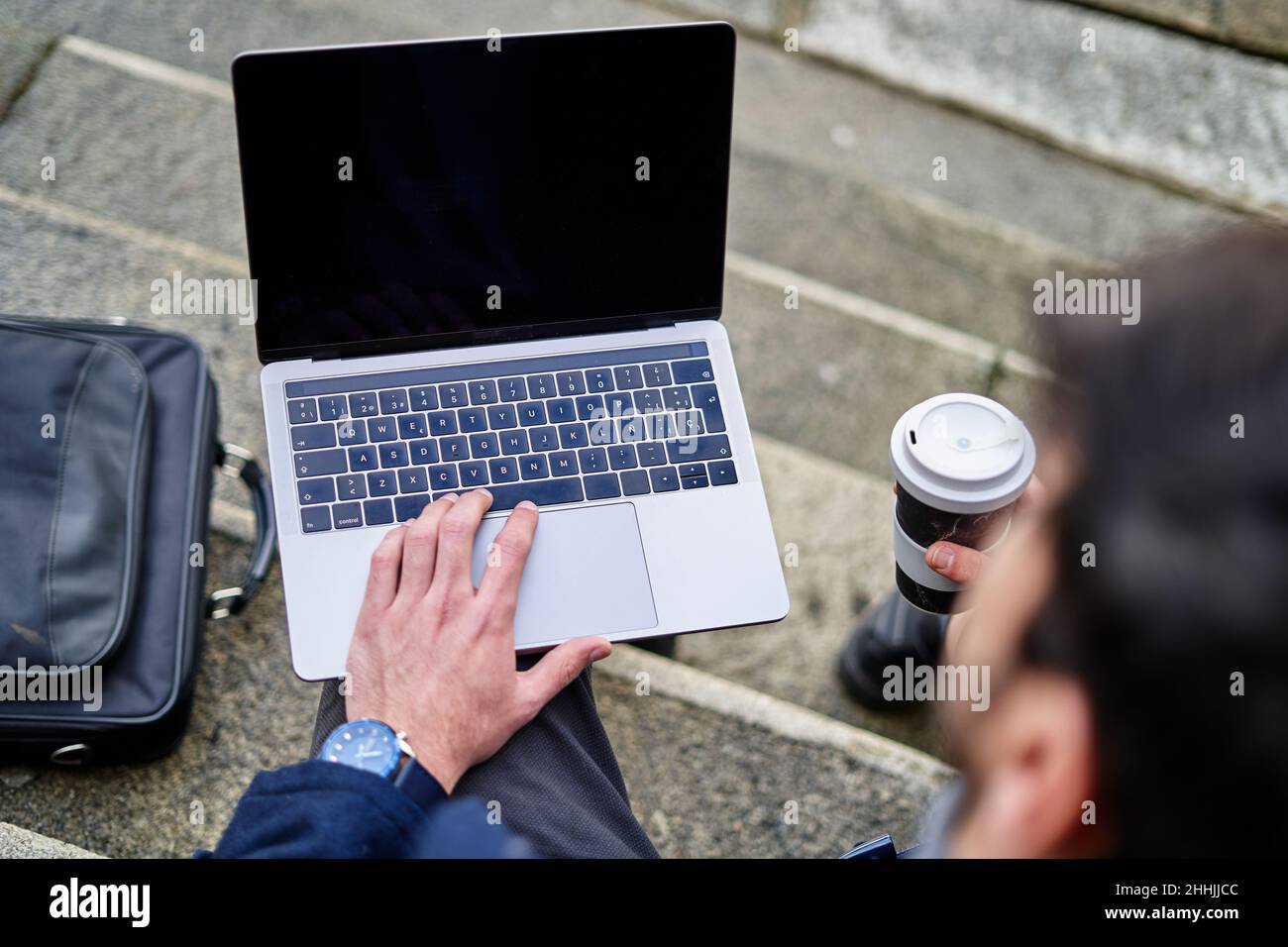 High angle back view of male student sitting on stone staircase and ...