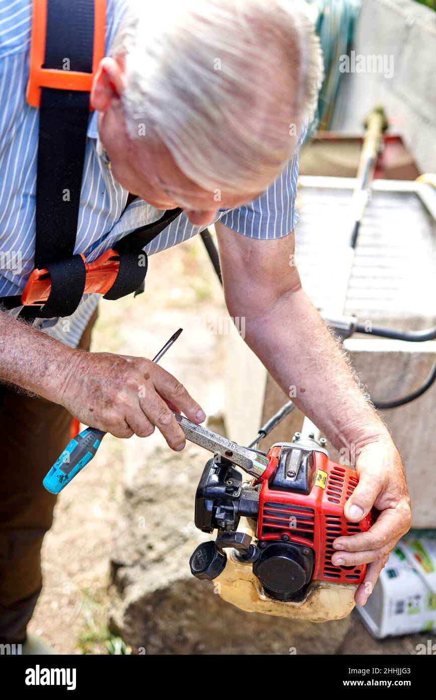 High angle of focused elderly male gardener fixing mechanism of broken ...