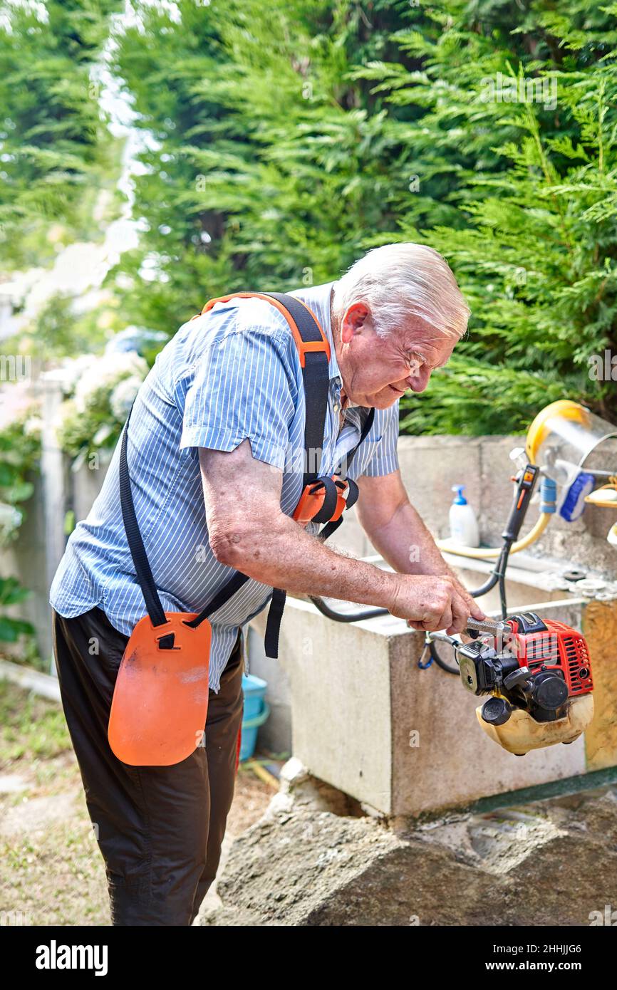 Concentrated elderly male gardener fixing mechanism of broken lawn ...
