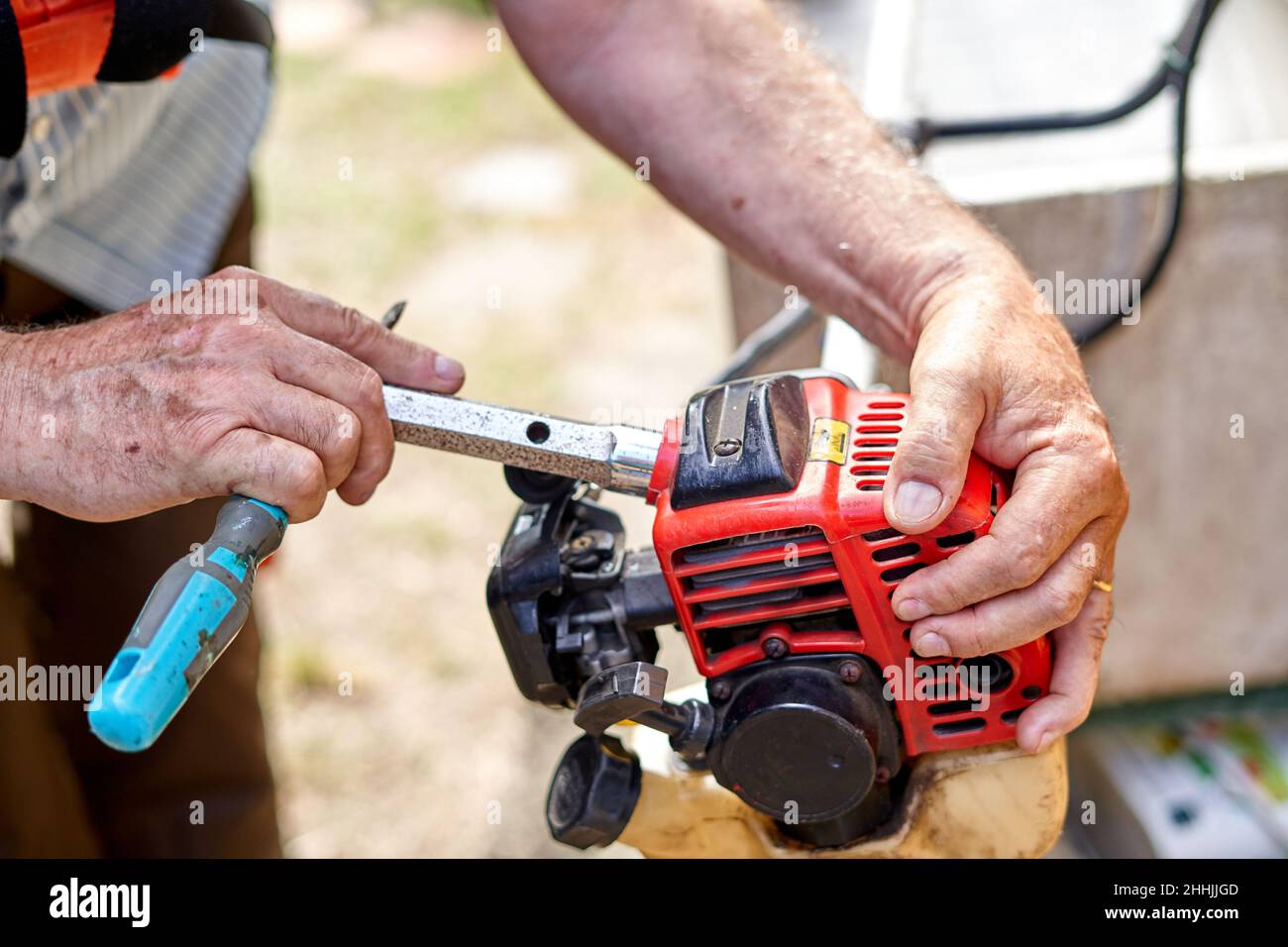 Crop elderly male gardener fixing mechanism of broken lawn trimmer with ...