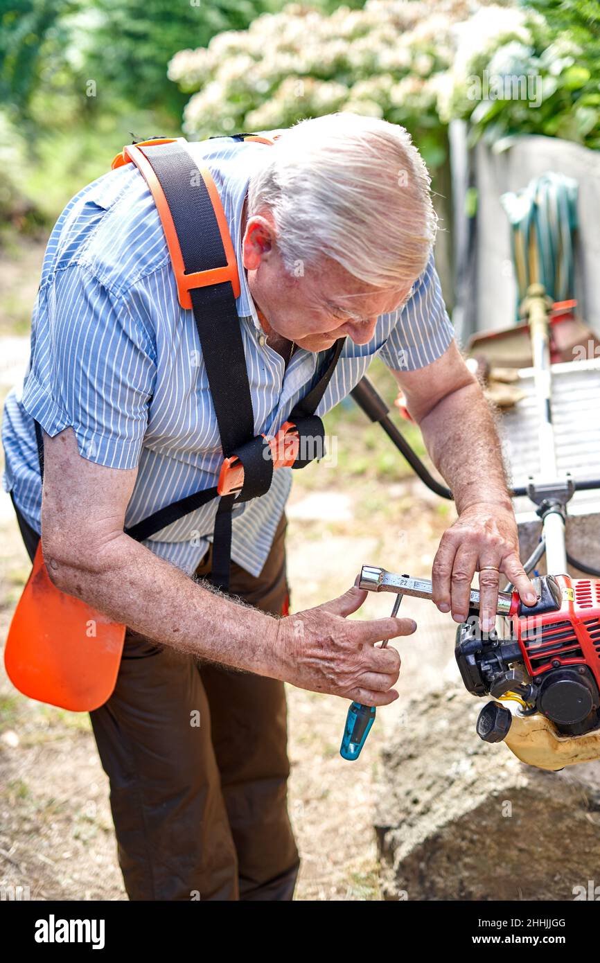 Concentrated elderly male gardener fixing mechanism of broken lawn ...