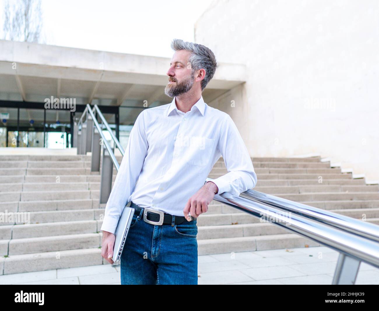 Confident male entrepreneur with modern netbook in hand leaning on ...