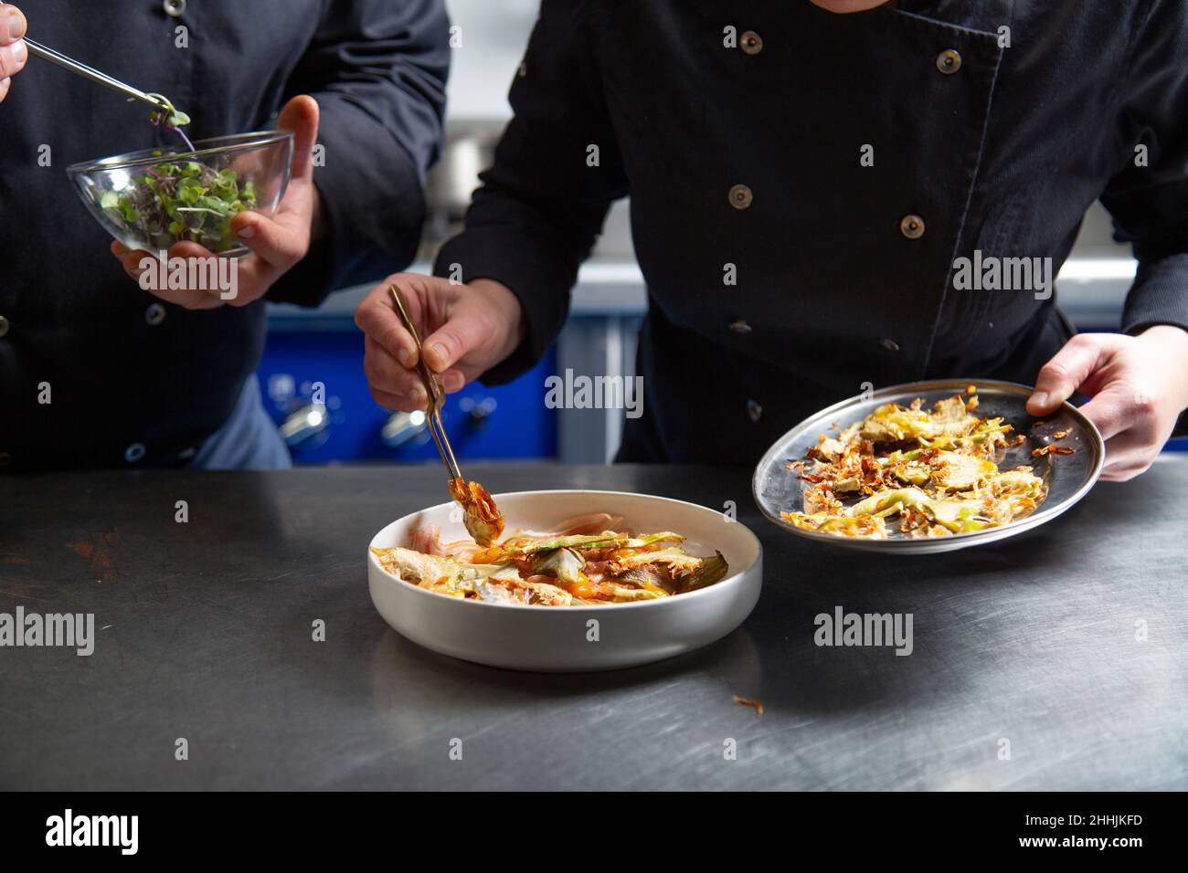 Anonymous male and female chefs arranging ingredients on bowl while ...