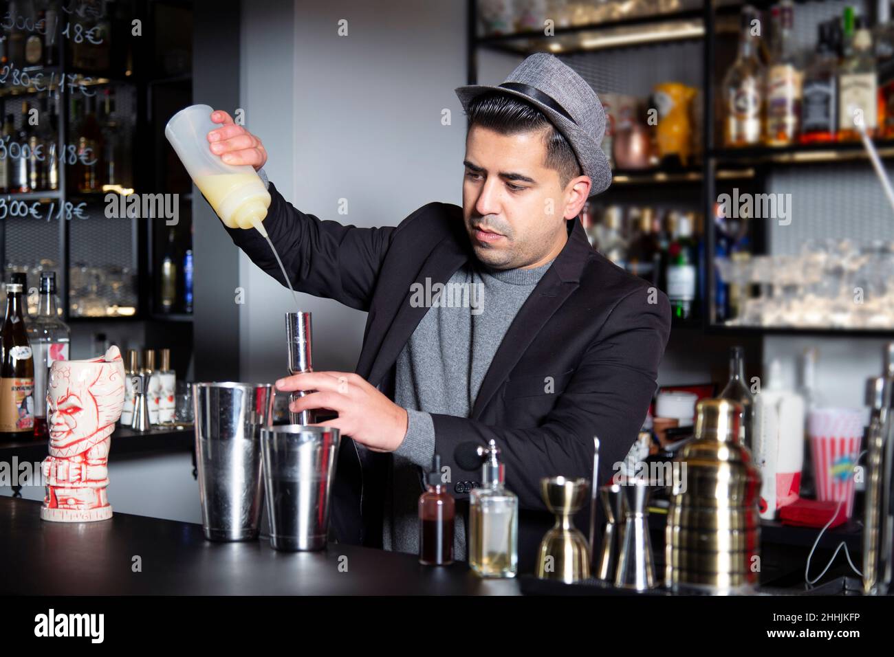 Male barkeeper pouring alcohol drink into jigger while making cocktail ...