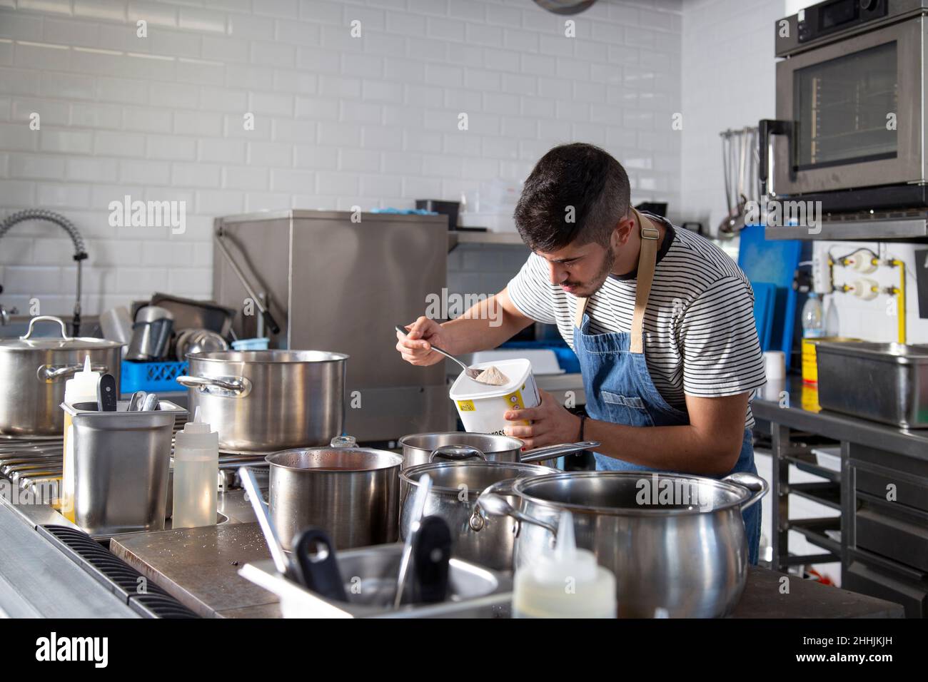 Focused young Hispanic male chef with dark hair in casual clothes and ...