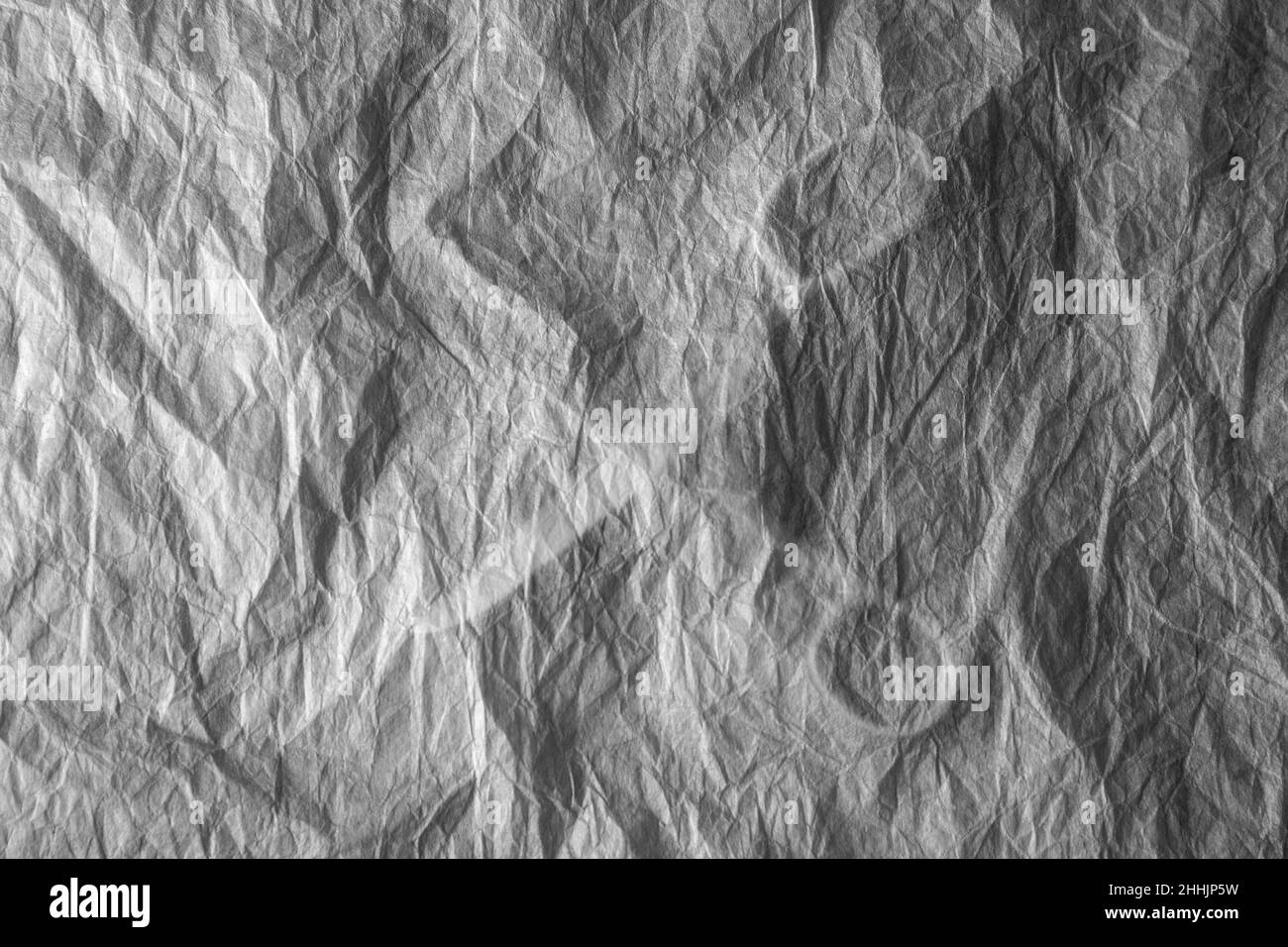 Top view of wrinkled textured translucent paper covering sharp scissors ...