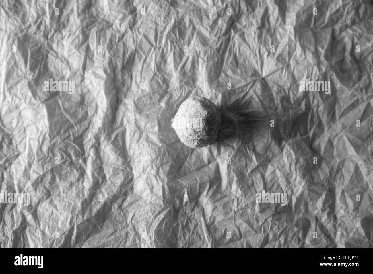 From above of hard rock and white paper ball placed on gray background ...