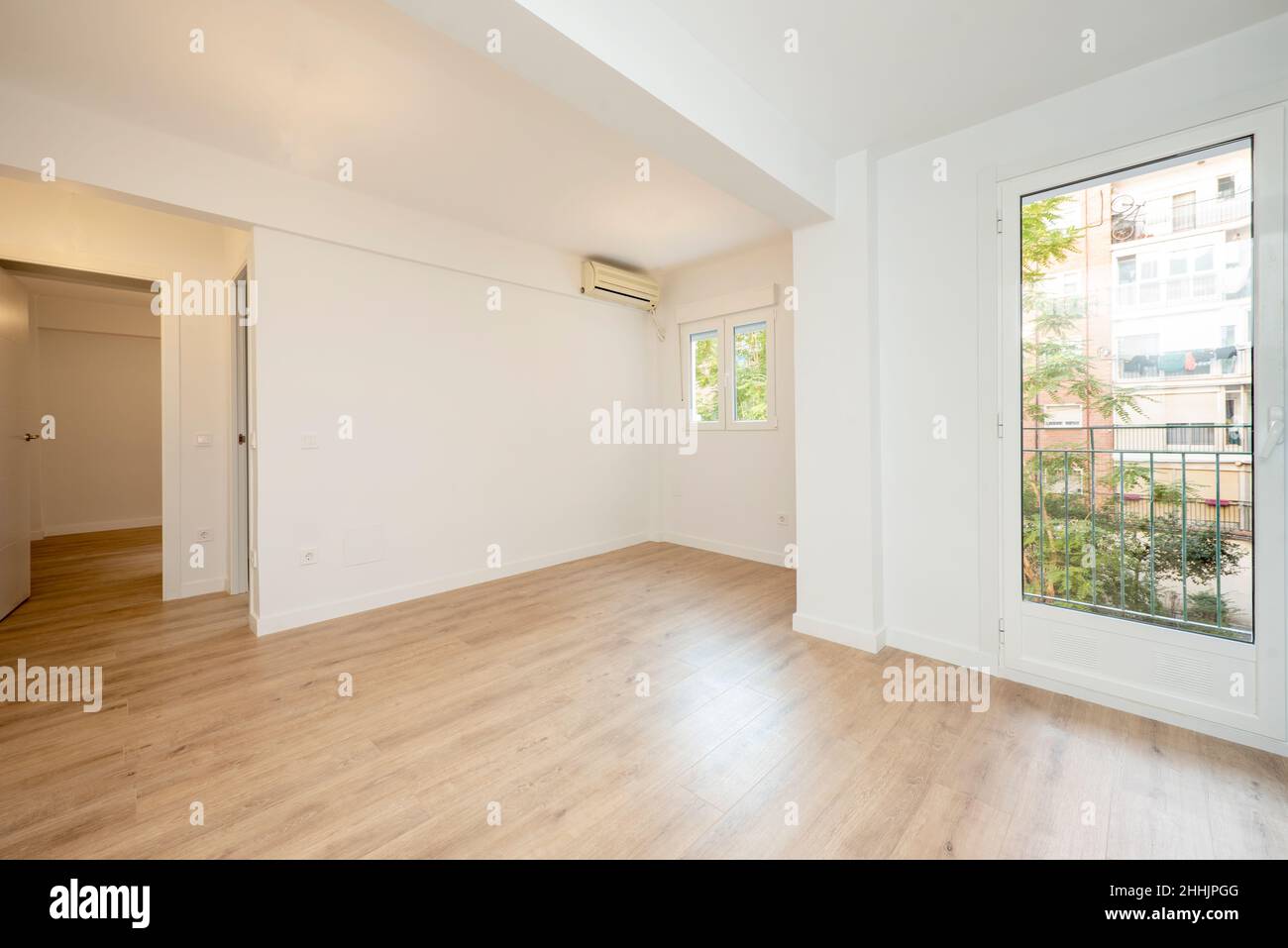 Empty living room with large window to one side, oak hardwood floors ...