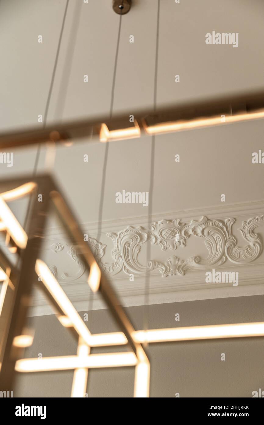 Low angle of hanging metal cube lamp against white wall with molding ...