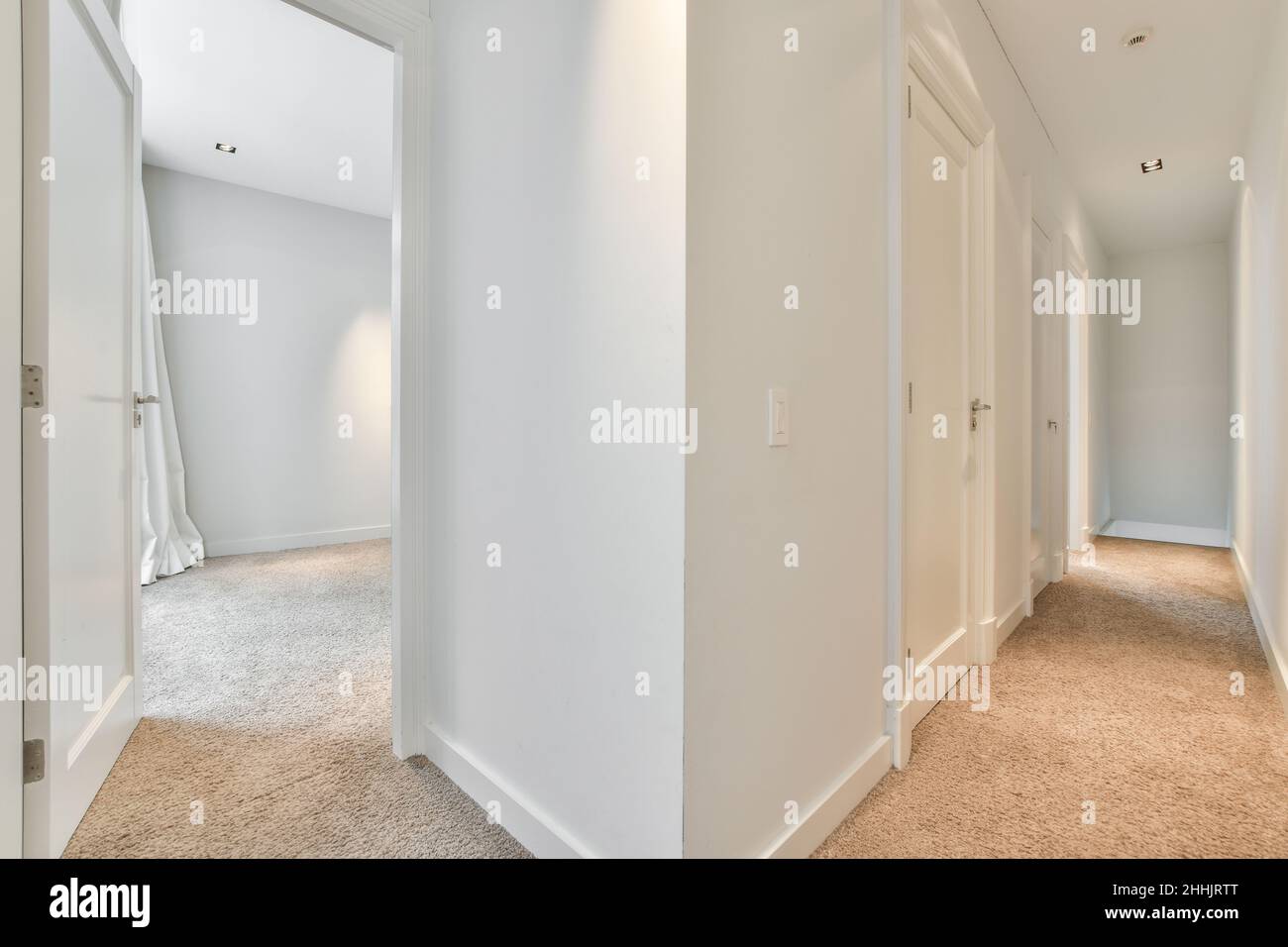 Perspective view of empty corridor with doors and room with white walls ...
