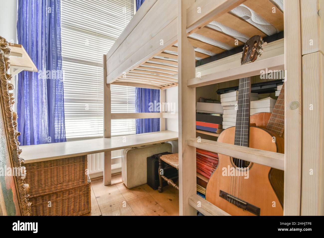 Interior of small teenager room with desk opposite window and guitar ...