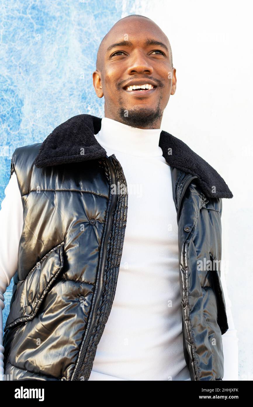 From below smiling bald African American male in stylish wear looking ...