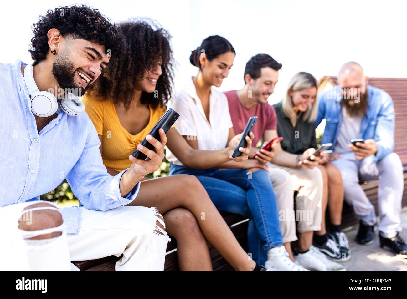 Happy young group of people using cell phone together while sitting ...