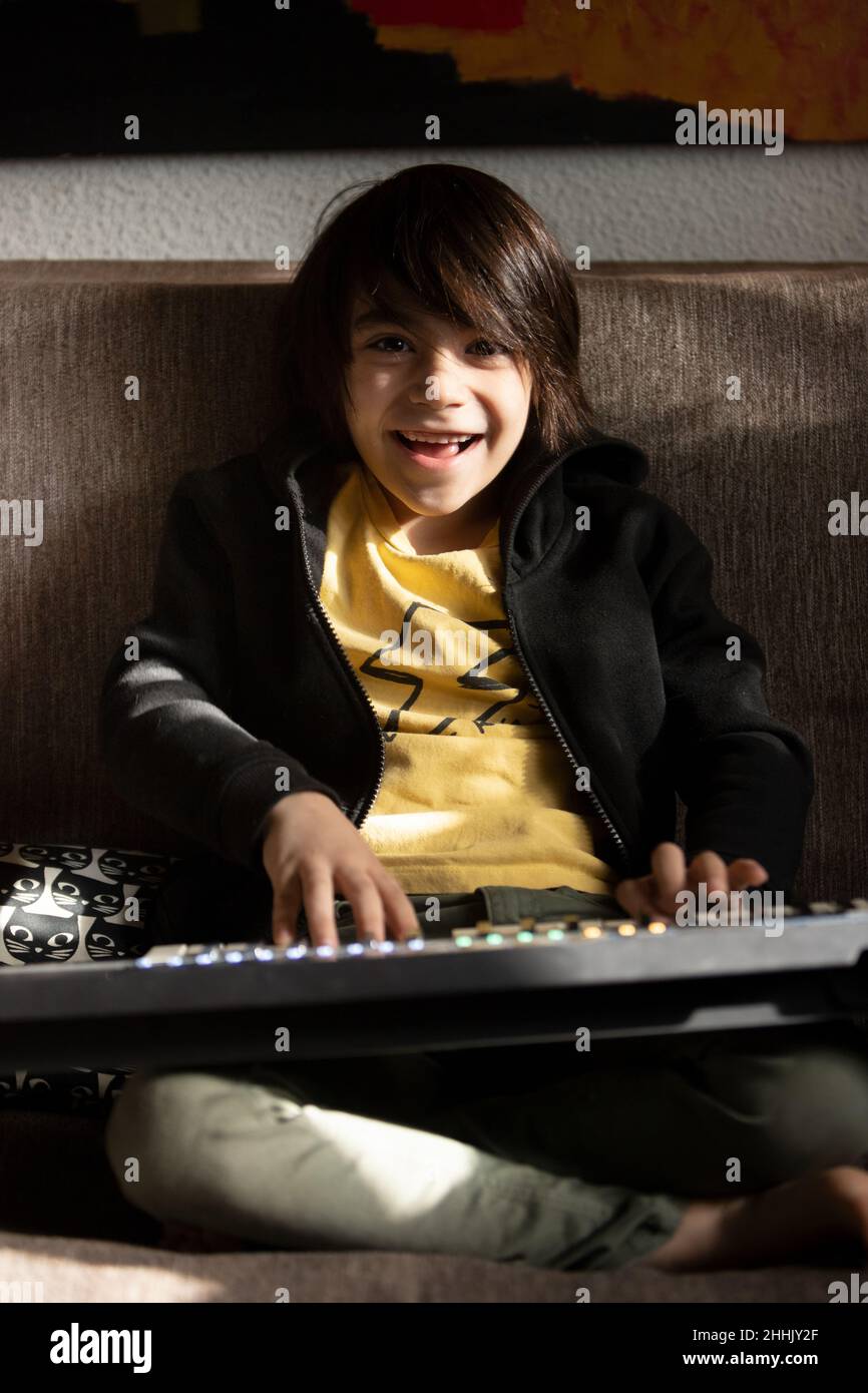Positive ethnic boy looking at camera with smile while playing melody ...