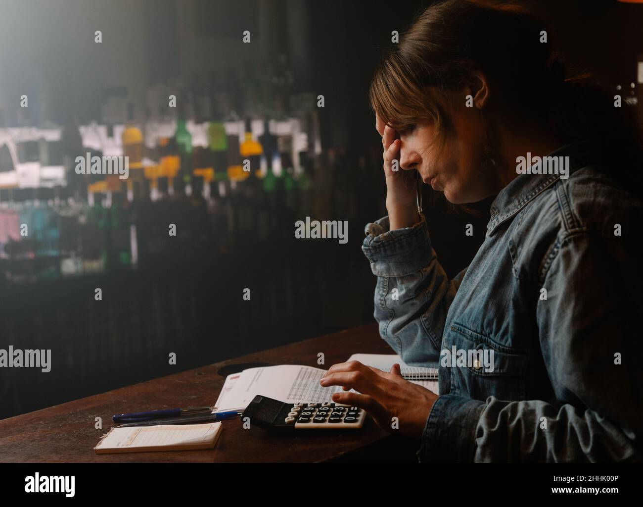 Side view of focused female worker using calculator to count income ...