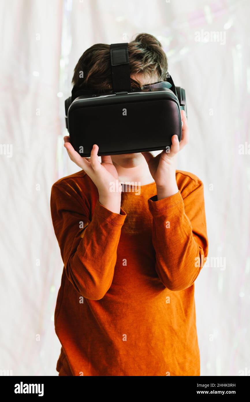 Child in modern VR goggles experiencing virtual reality in studio on ...