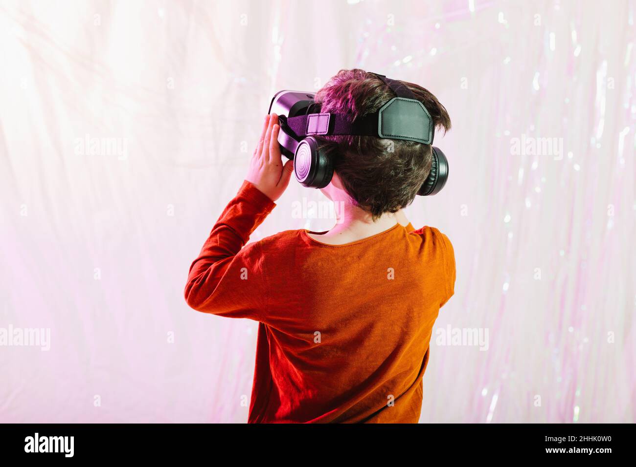 Back view of unrecognizable child in modern VR goggles experiencing ...