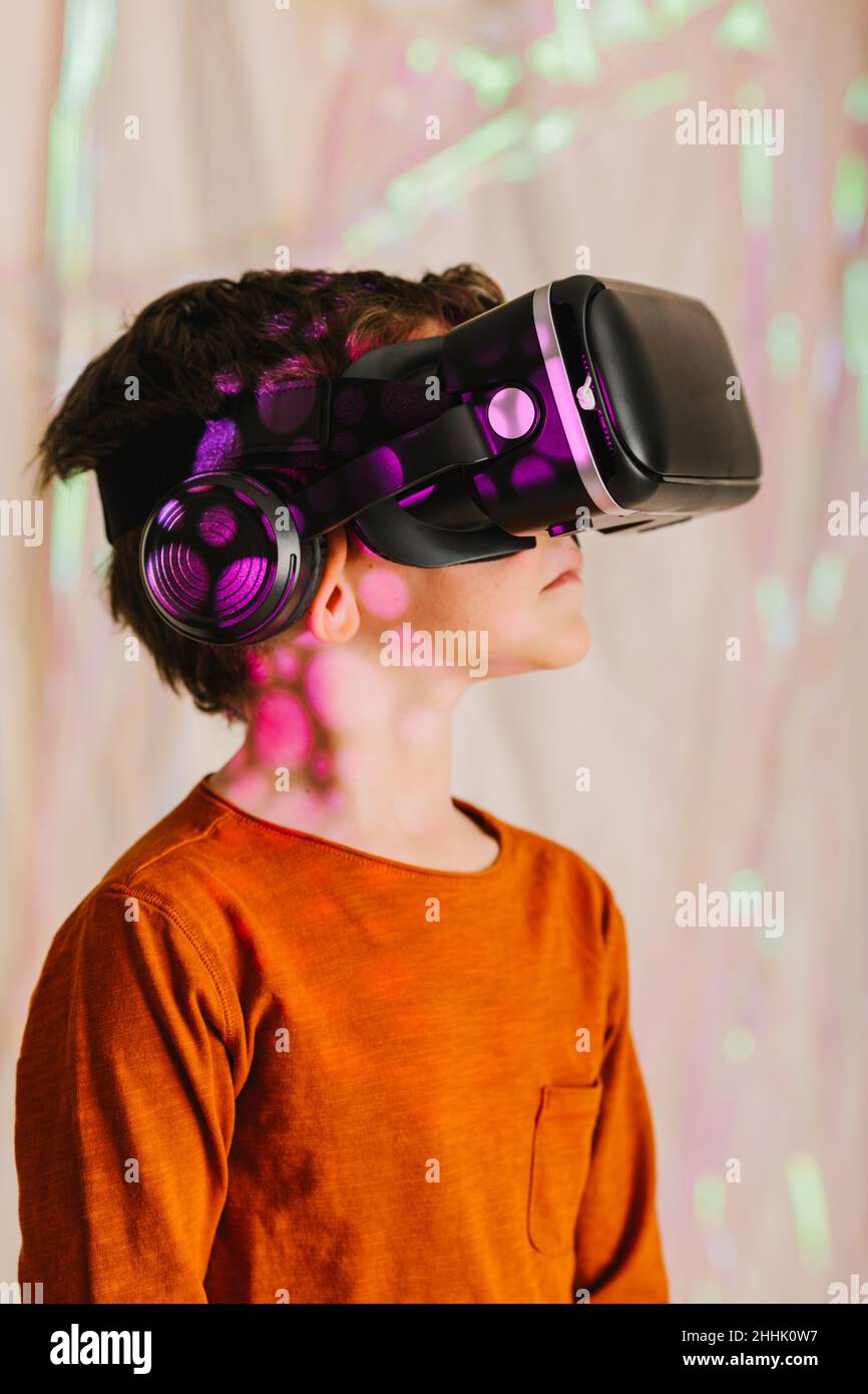 Side view of child in modern VR goggles experiencing virtual reality in ...
