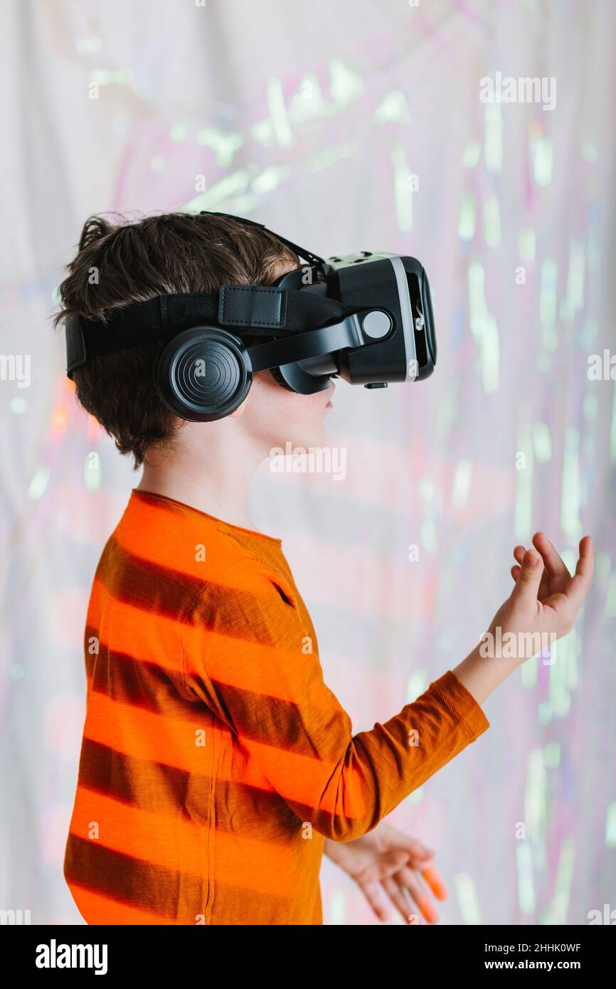 Side view of child in modern VR goggles experiencing virtual reality in ...