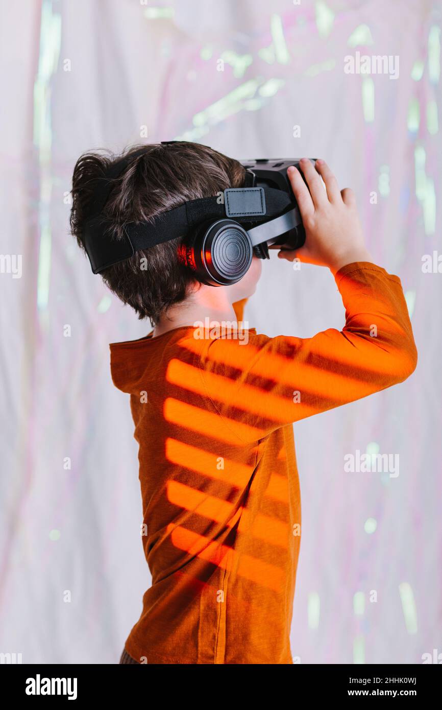 Side view of child in modern VR goggles experiencing virtual reality in ...