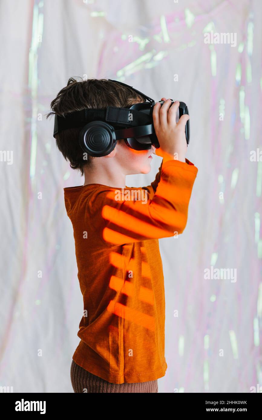 Side view of child in modern VR goggles experiencing virtual reality in ...