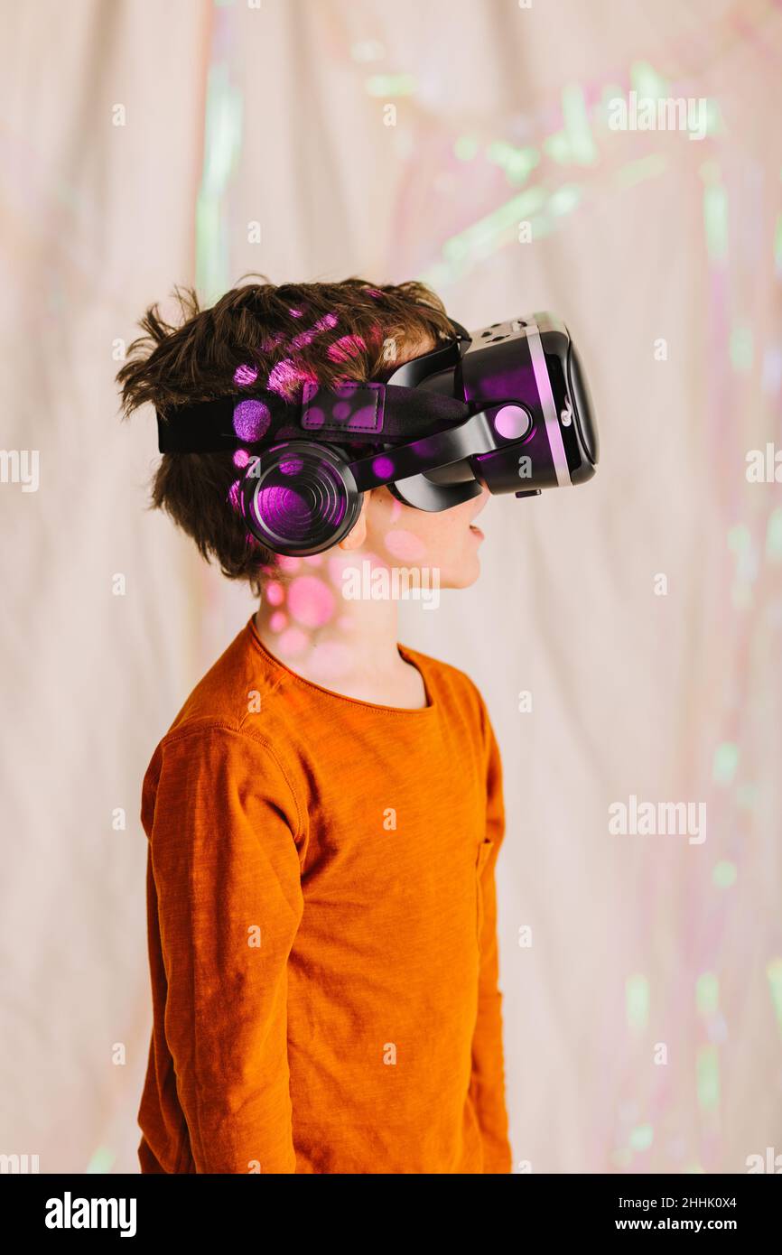 Side view of child in modern VR goggles experiencing virtual reality in ...