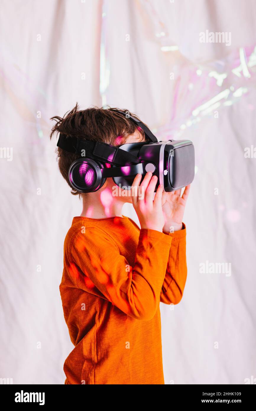 Side view of child in modern VR goggles experiencing virtual reality in ...