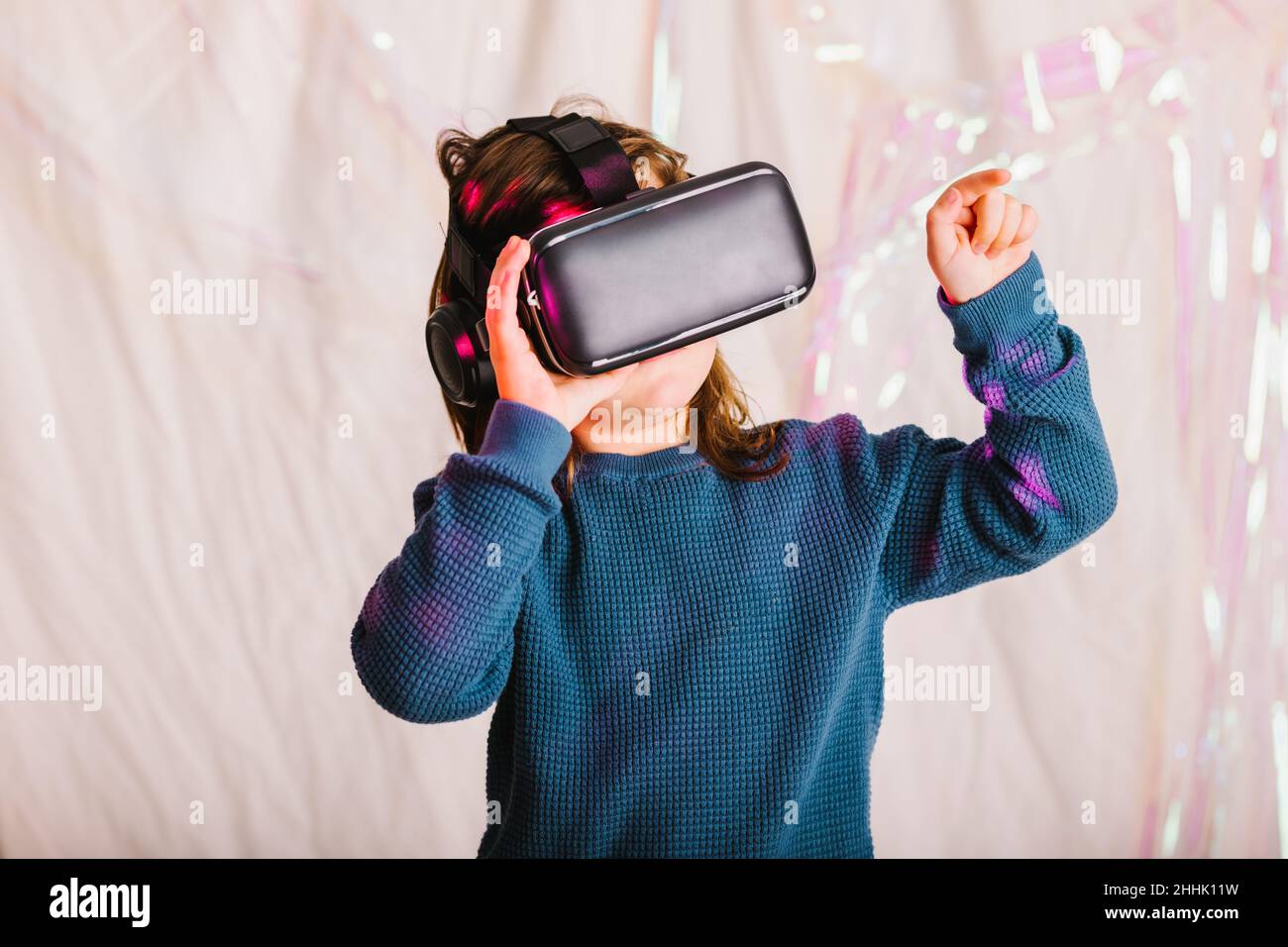 Child in modern VR goggles experiencing virtual reality in studio on ...