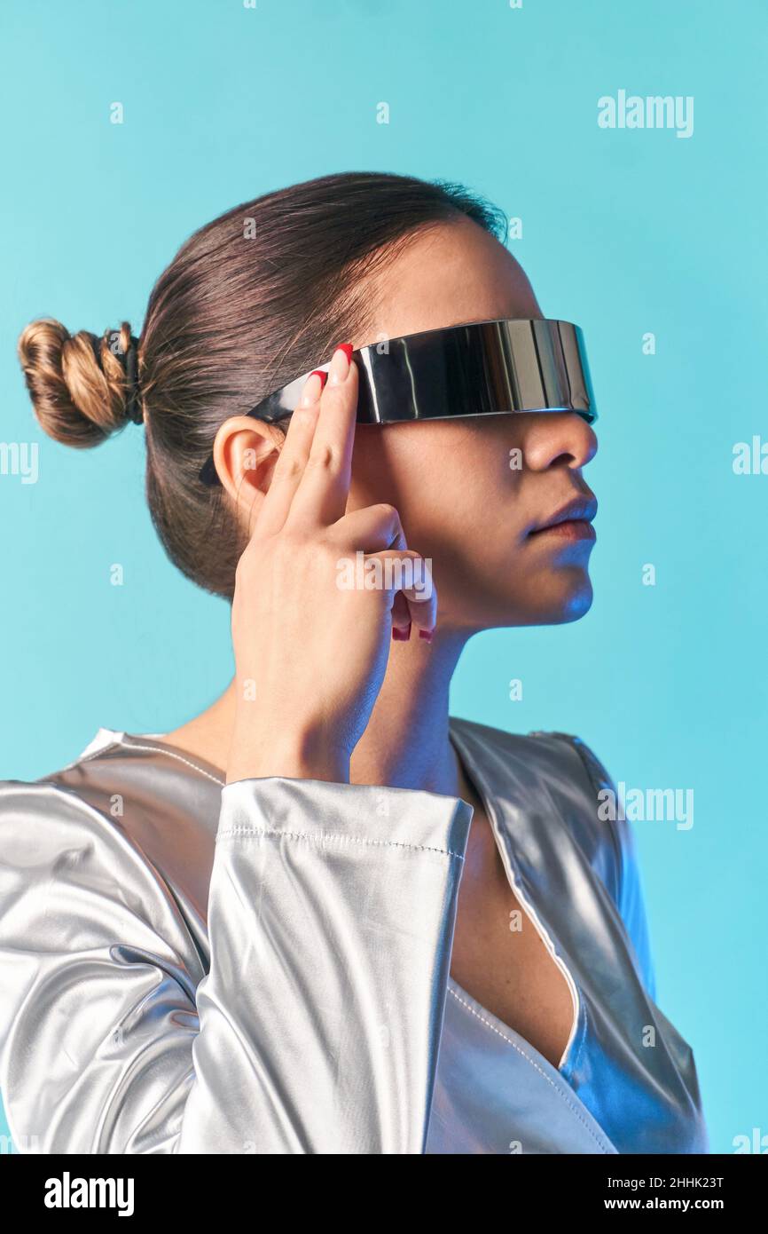 Young trendy ethnic lady with dark hair in modern mirrored VR goggles ...