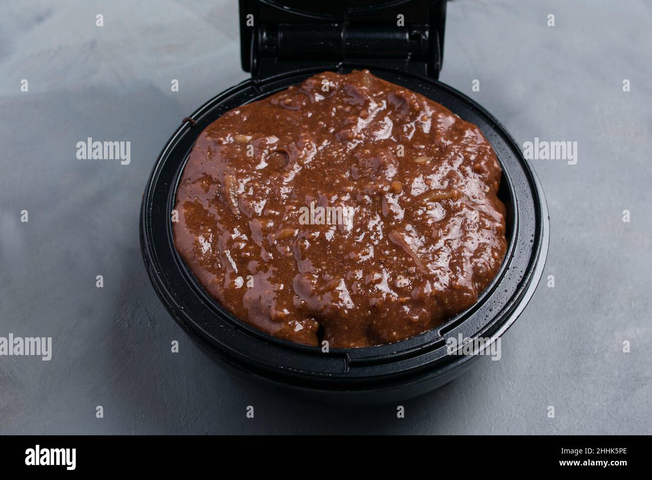 From above of raw chocolate waffle batter on black waffle maker placed ...