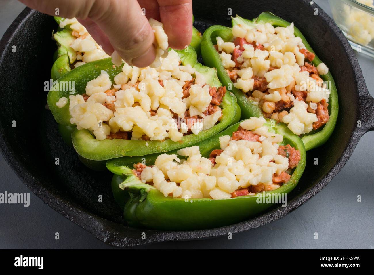 Crop anonymous person adding cheese on green bell peppers with pizza ...