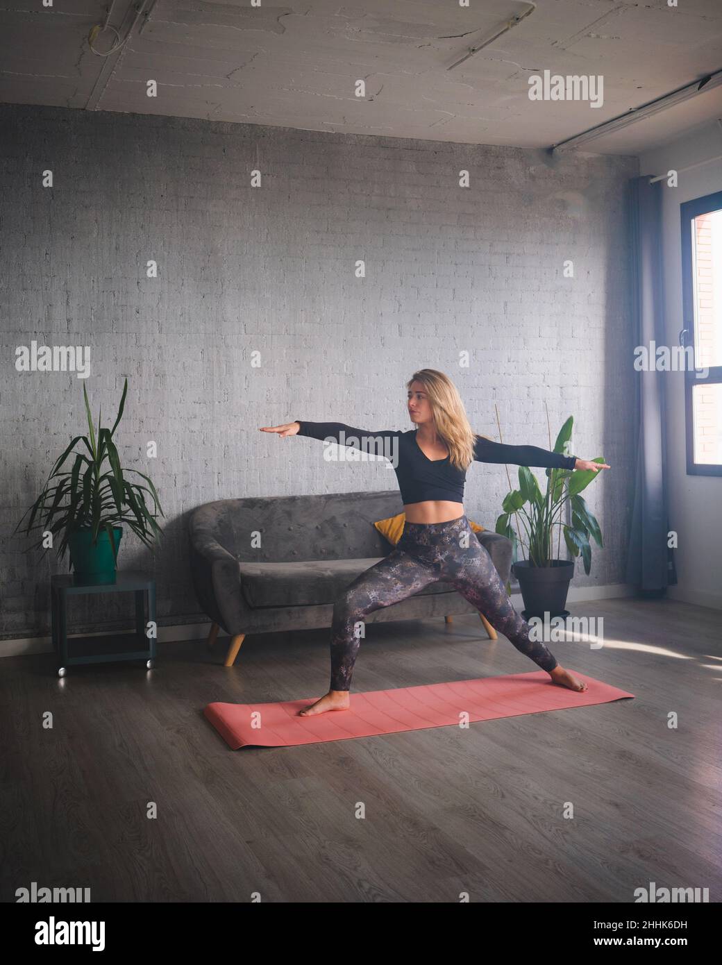 Full body of barefoot slim female doing Virabhadrasana B posture for ...