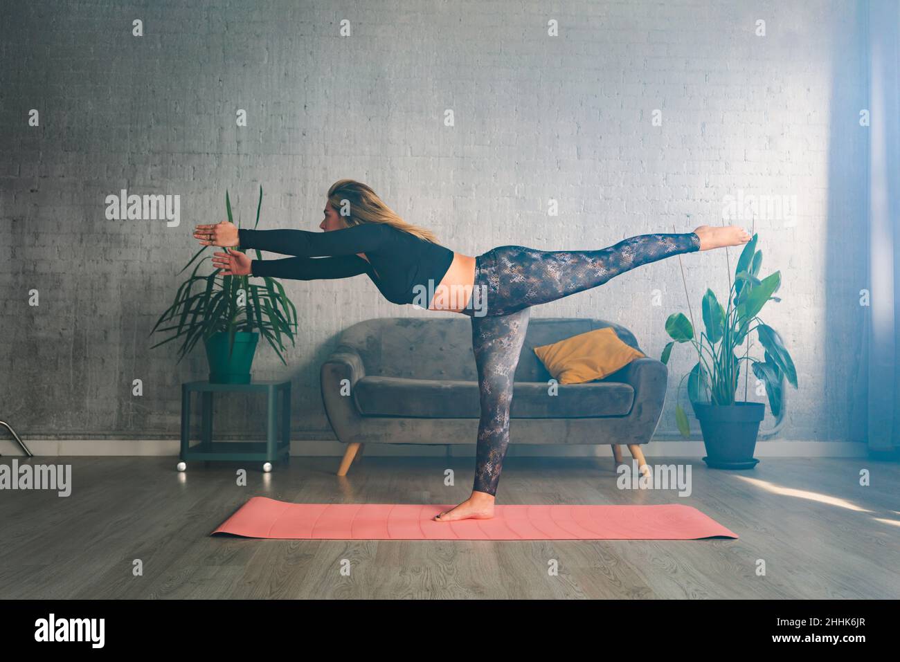 Full body side view of fit female standing on one leg and outstretching ...
