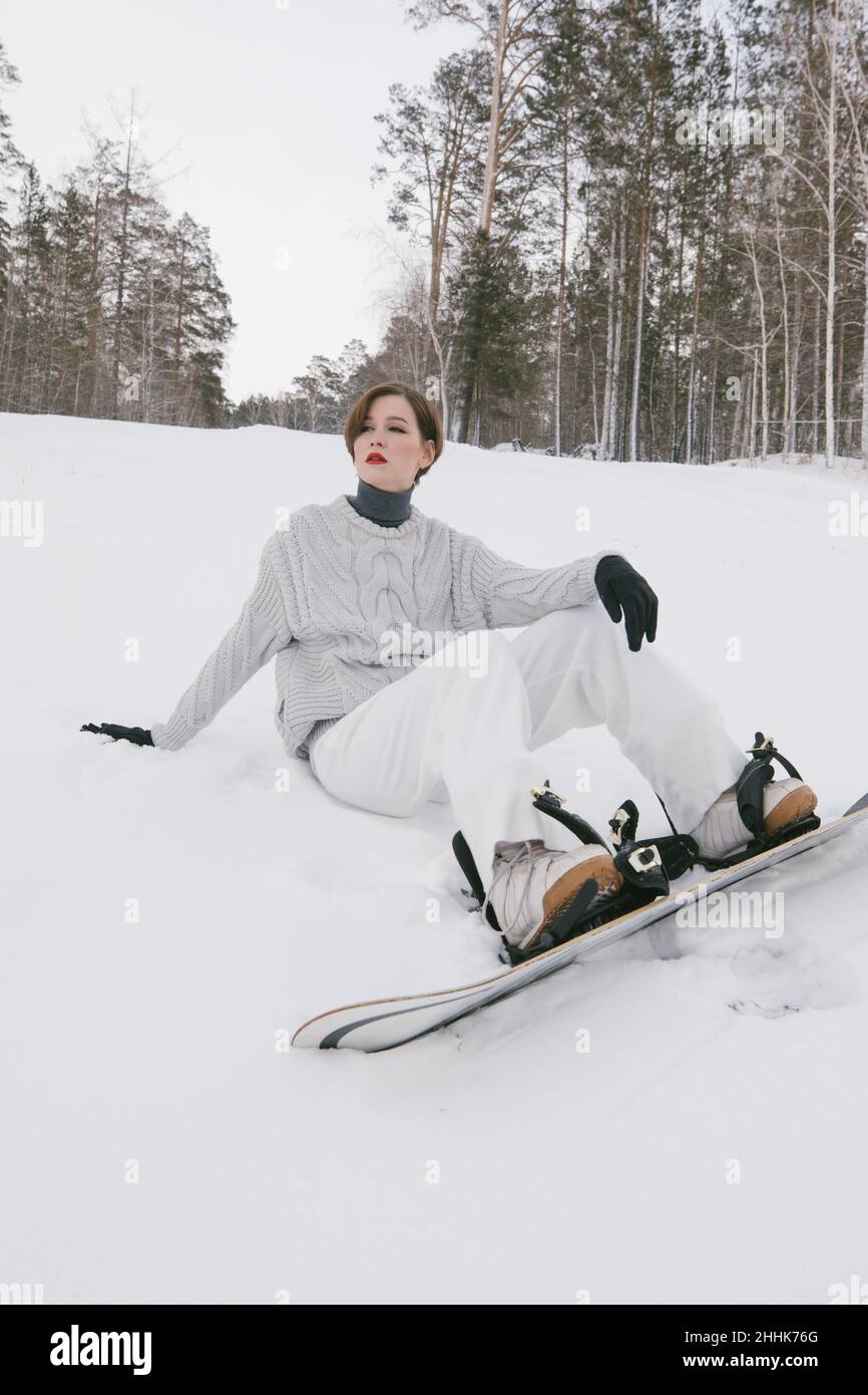 Fashion model girl sitting on a snowboard in the snow Stock Photo - Alamy