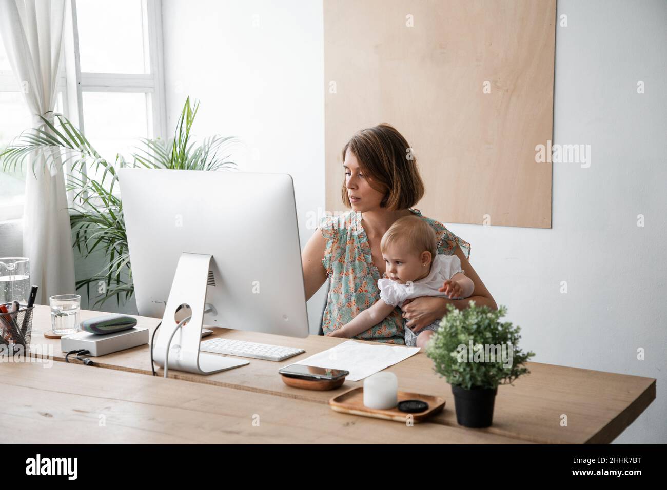 Concentrated female freelancer with cute baby working remotely on ...