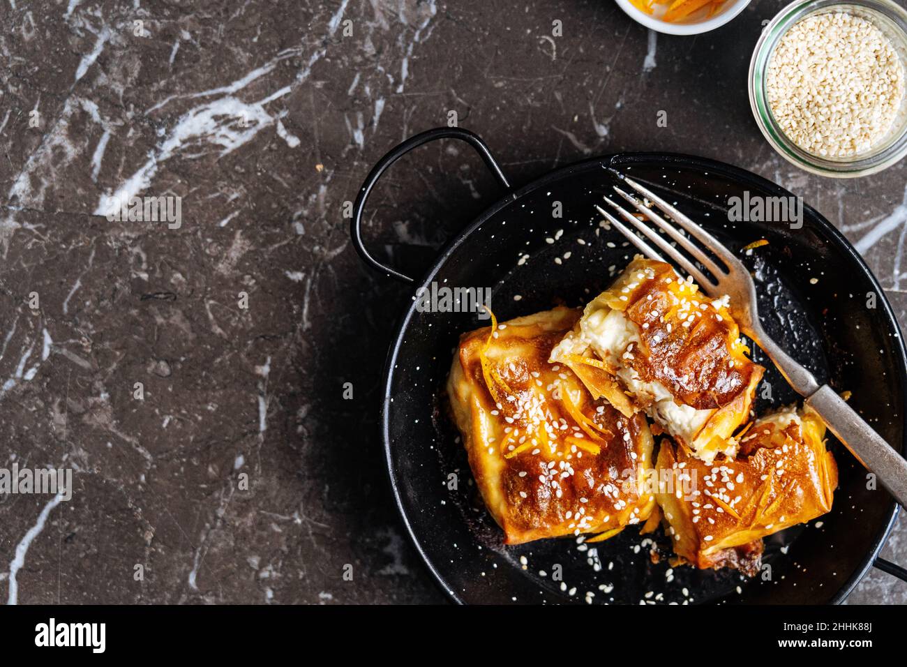 Top view of sweet tasty pastry with sesame seeds served on black plate ...