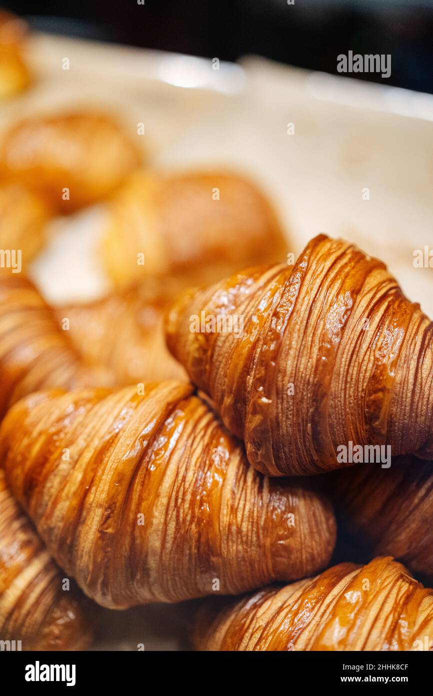 Heap of tasty crispy brown croissants placed on parchment in showcase ...