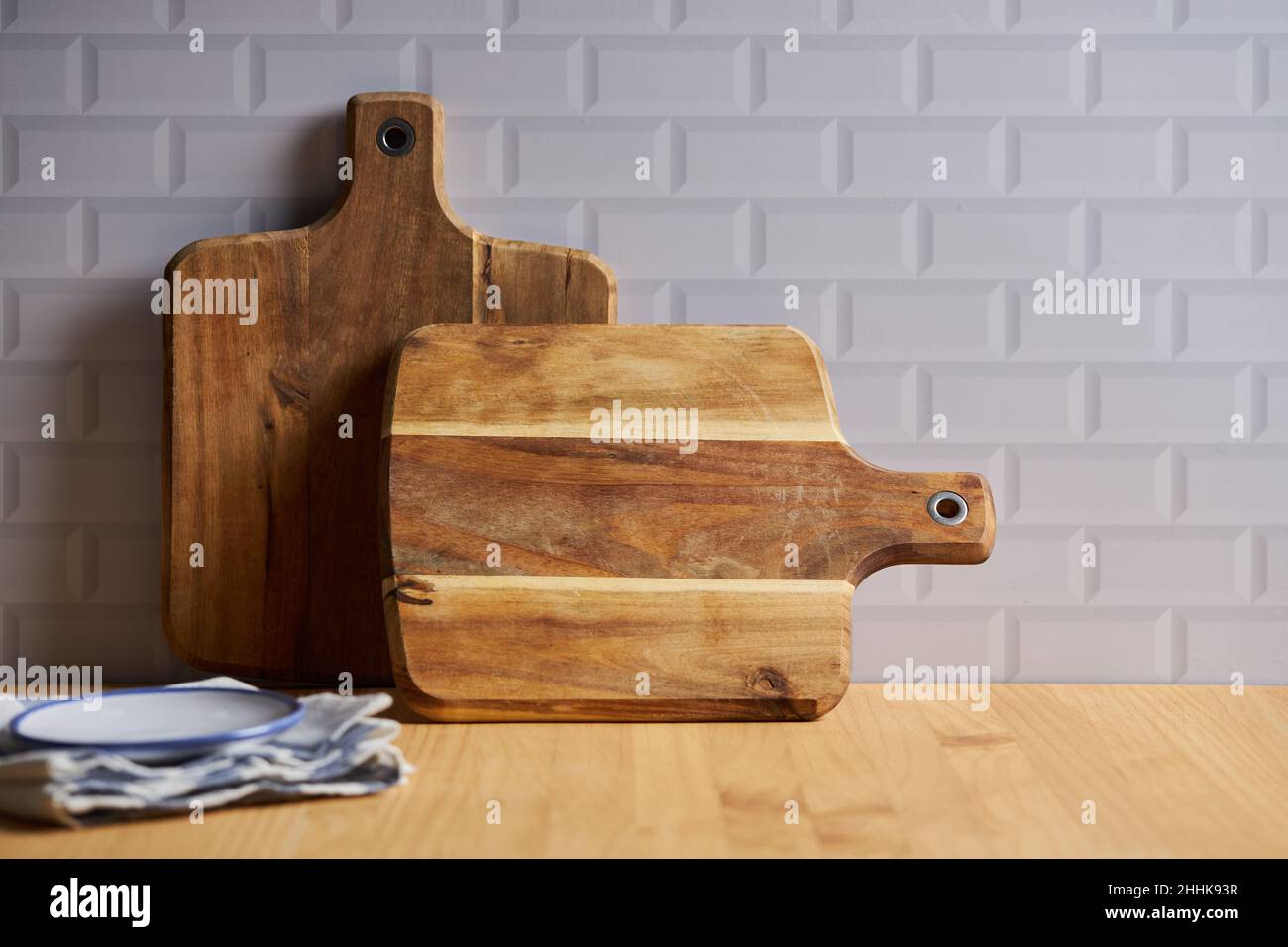 Wooden chopping boards placed near wall on table with bowl in light ...