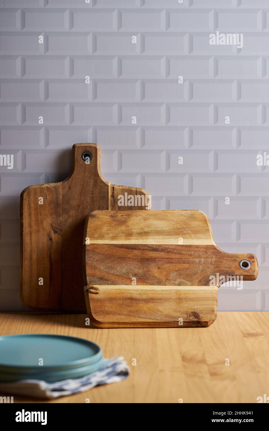 Wooden chopping boards placed near wall on table with bowl in light ...