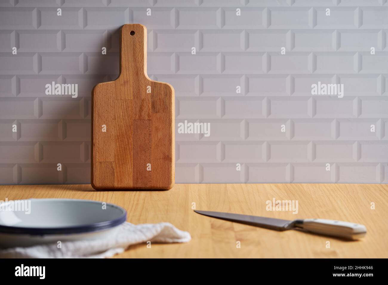 Wooden chopping board placed near wall on table with bowl and knife in ...
