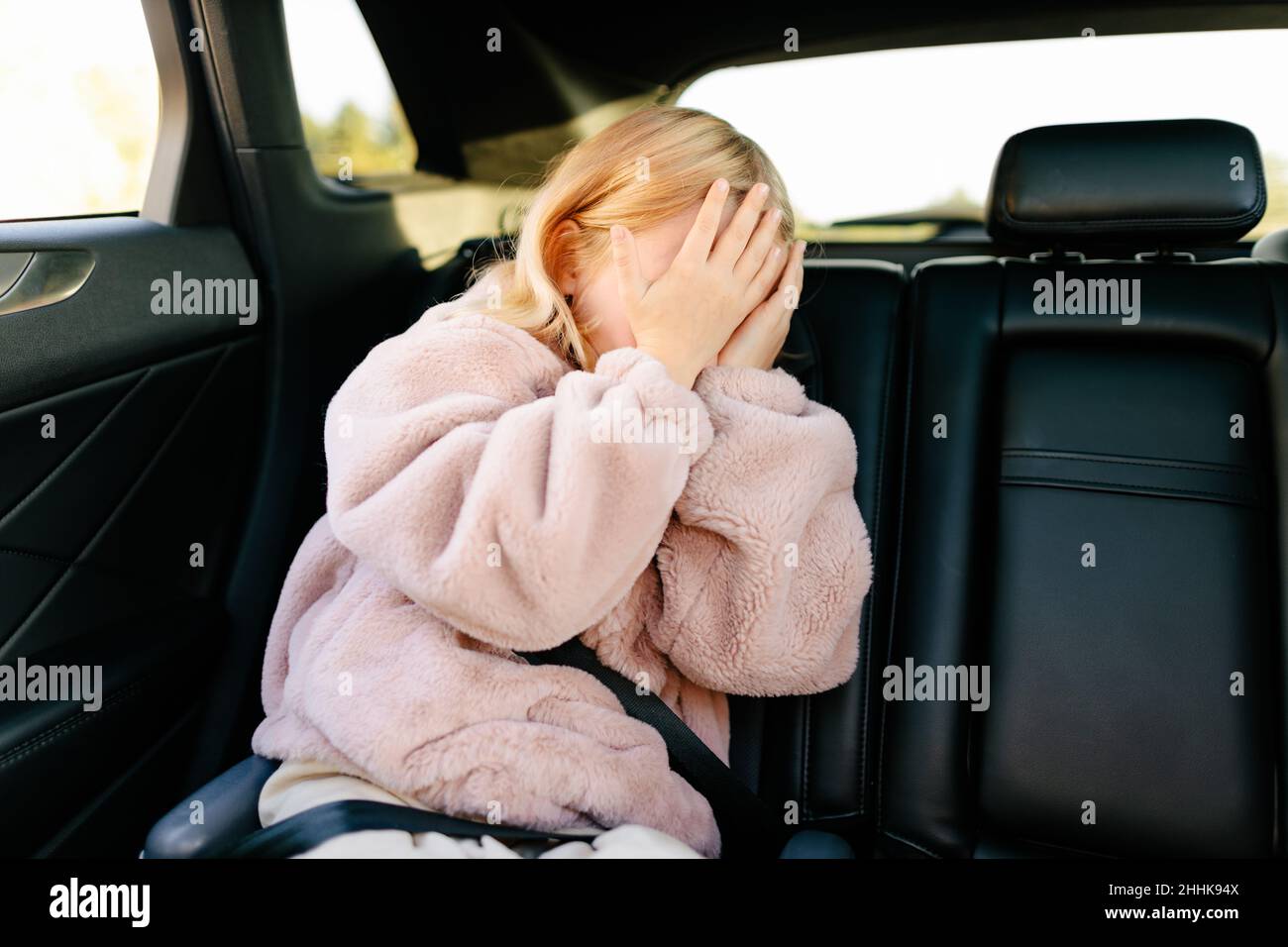 Anonymous girl with blond hair covering face with hands and hiding ...