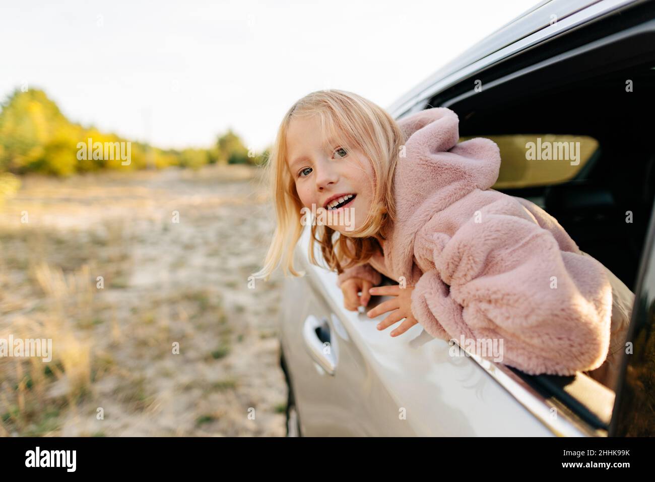 Astonished girl with blond hair looking out of automobile window with ...