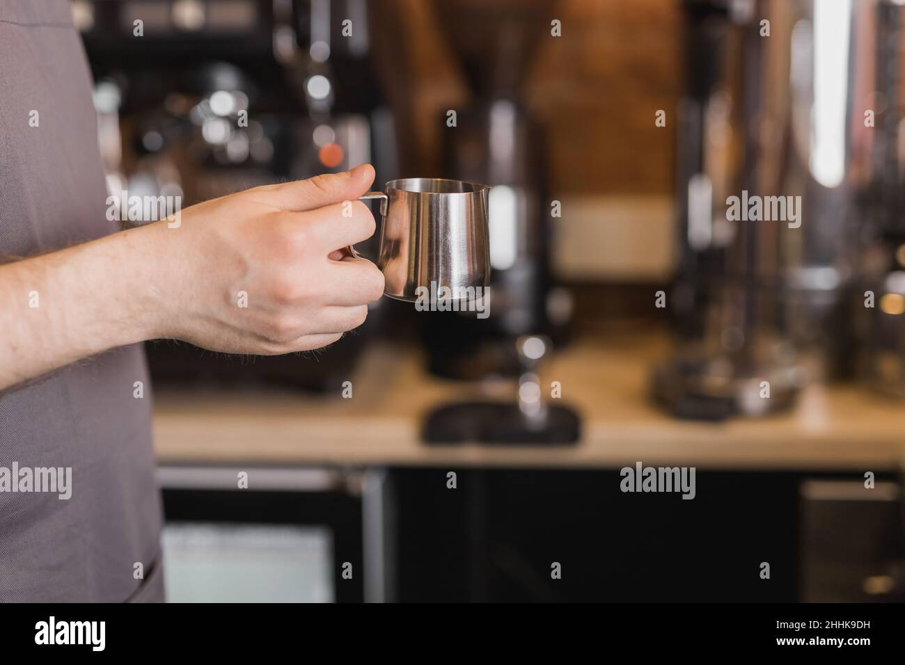 Crop anonymous barista with stainless pitcher preparing drink in coffee ...