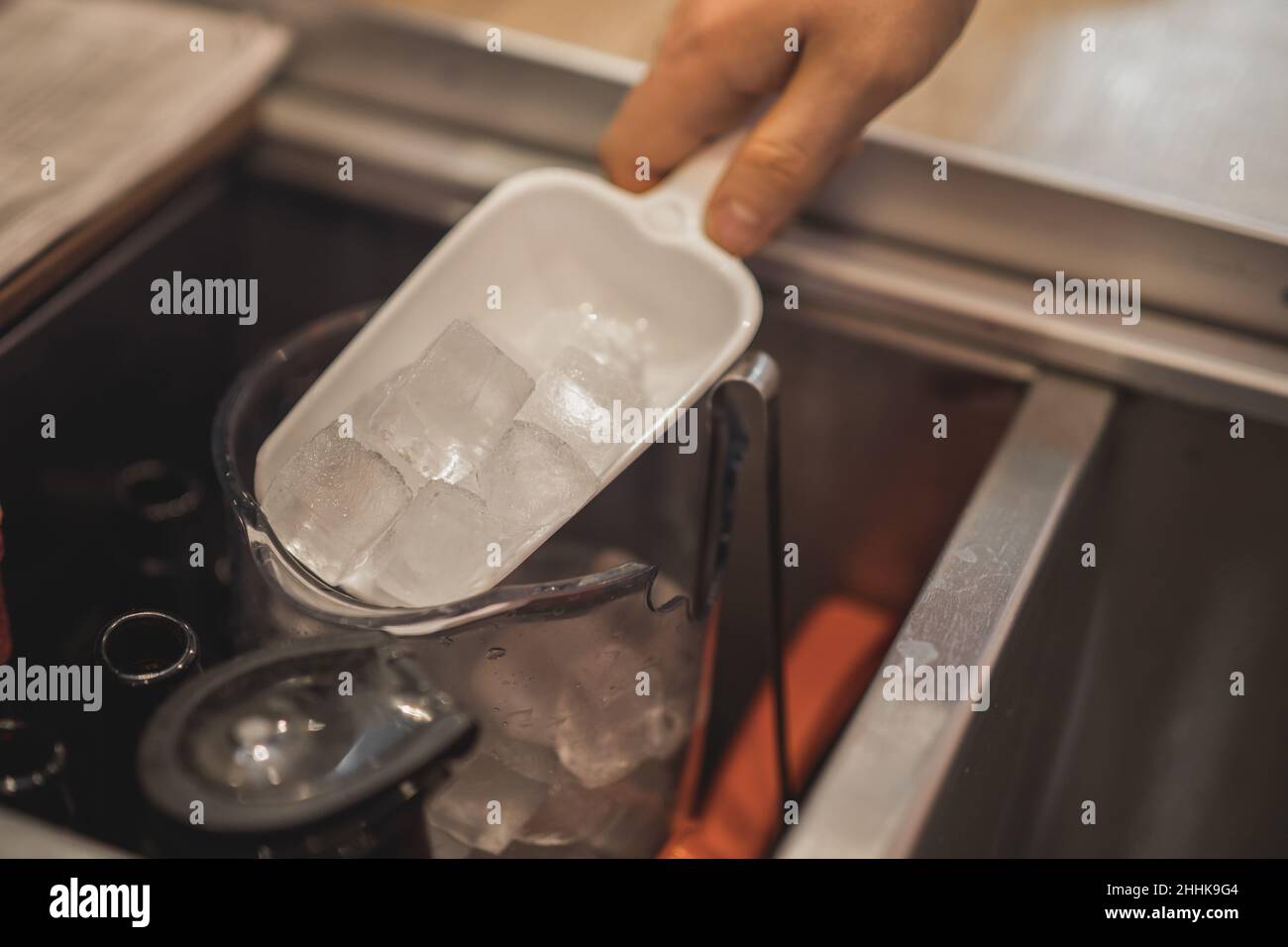 High angle of crop anonymous person taking ice cubes from jug for ...